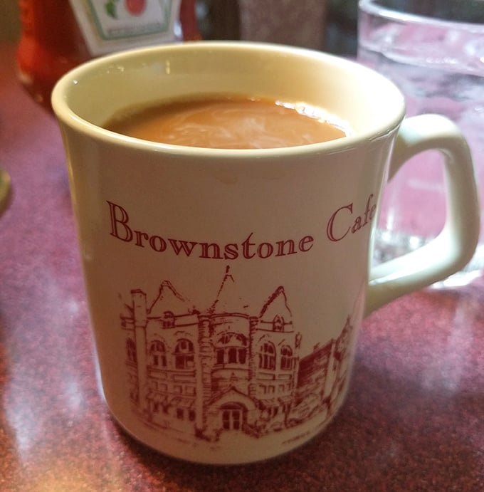The official morning handshake at Brownstone Cafe—a sturdy mug of coffee featuring the building's historic facade. Caffeine with a side of architecture.