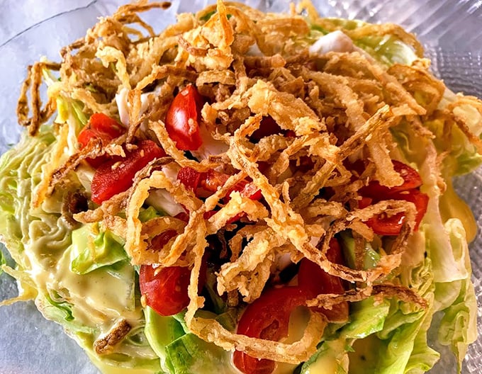 A salad that doesn't apologize for being a salad—crisp greens topped with those addictive fried onion wisps that turn vegetables into an event.