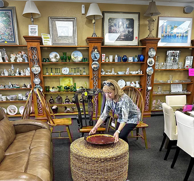 A volunteer arranges home décor items in a display that could easily be mistaken for an upscale furniture store vignette.
