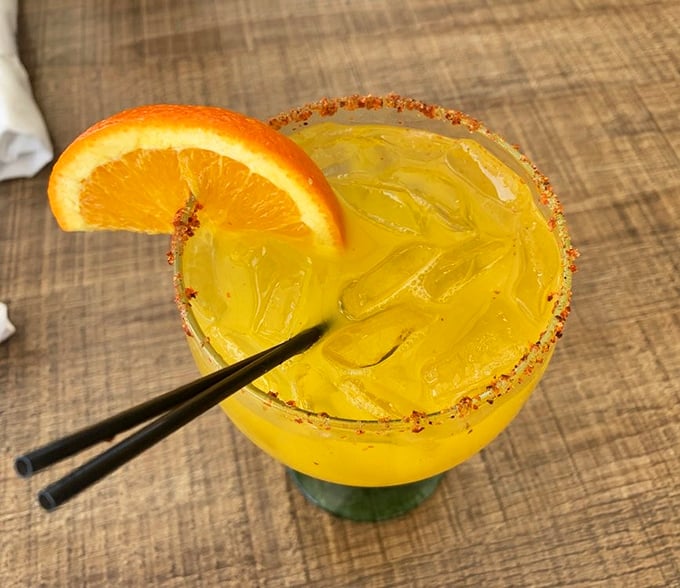 A sunshine-colored cocktail with a chili-salt rim—Miami in a glass, where every sip feels like a mini vacation.