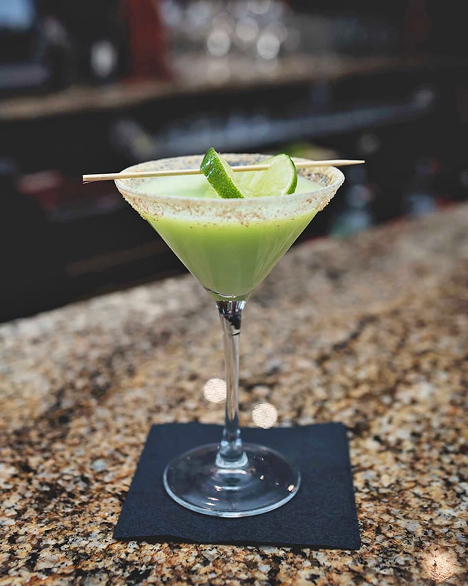 A vibrant cocktail that's dressed better than most people at the party. This isn't just a drink—it's liquid entertainment with a lime hat.