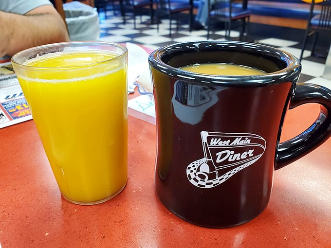Orange juice so vibrant it could power a small city, sitting beside the diner's signature mug—a vessel that's witnessed countless morning revelations and refills.