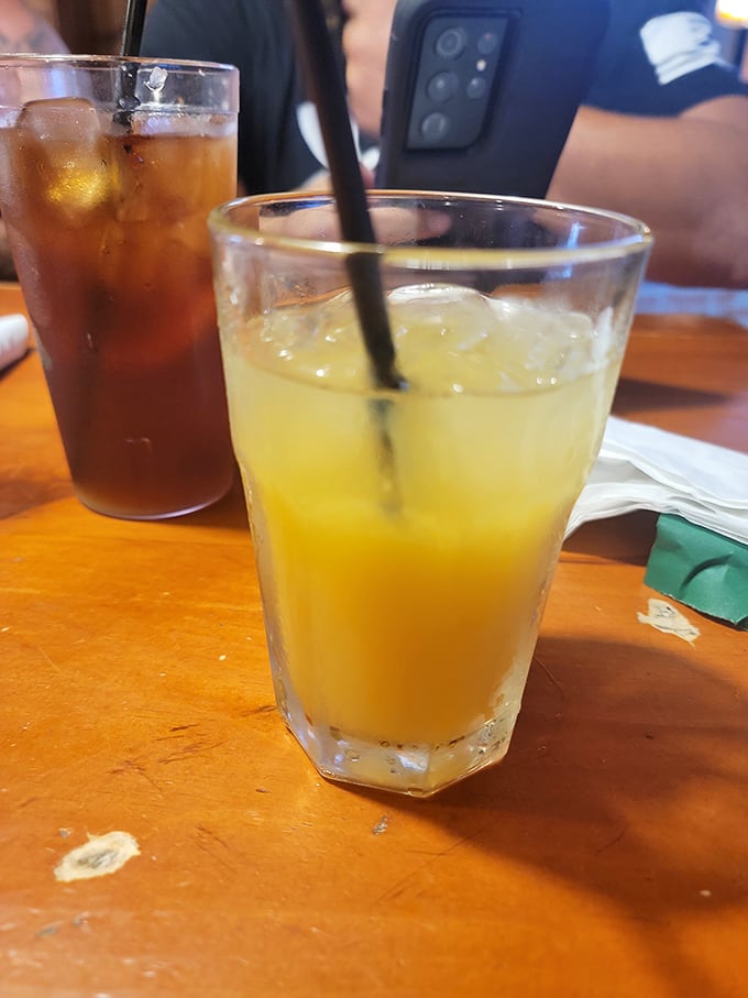 Cold drinks on a worn wooden table—the universal signal that good conversation and better food are moments away.