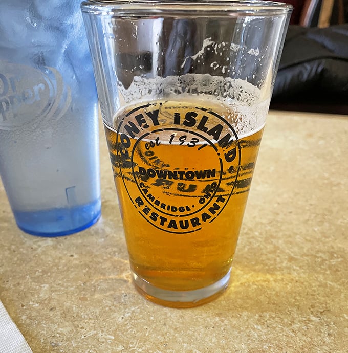The branded pint glass holds liquid gold, a perfect companion to those famous Coney dogs and a testament to simple pleasures done right.