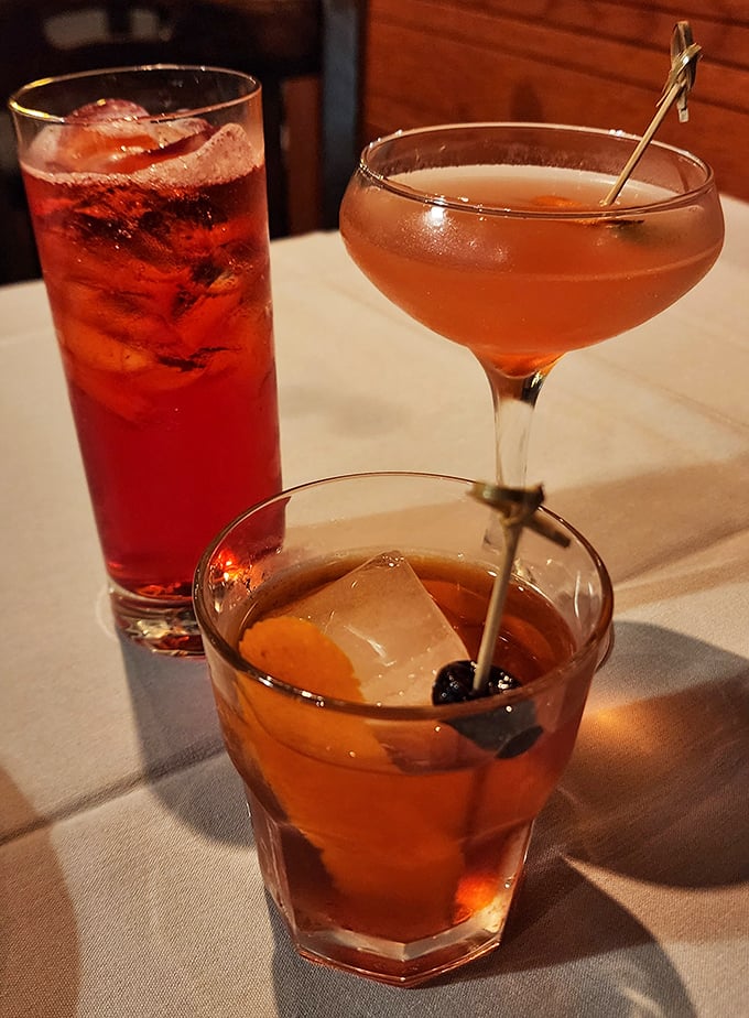 The cocktail trinity: a classic Old Fashioned, something pink and sophisticated, and that ruby-red concoction—liquid companions for your seafood adventure.
