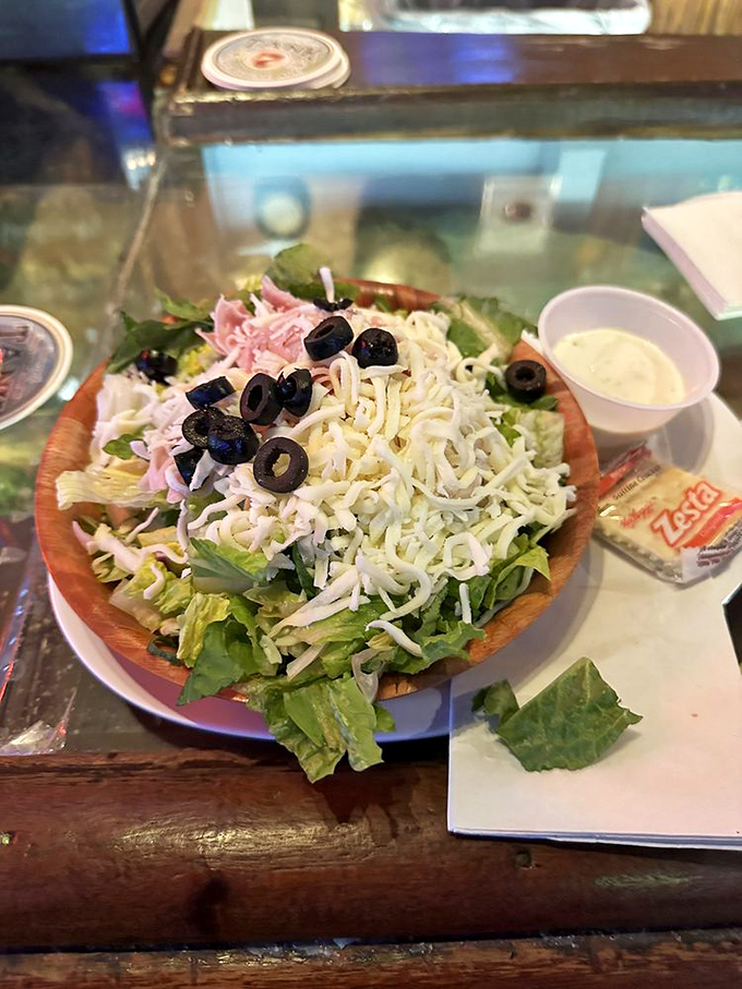 This isn't just a salad—it's a garden party in a wooden bowl, where cheese and olives mingle with the leafy guests of honor.