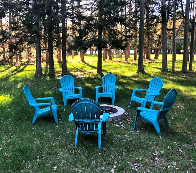 Adirondack chairs arranged in nature's conference room, where the only agenda item is relaxation. Blue chairs against green grass—Michigan's unofficial summer flag.