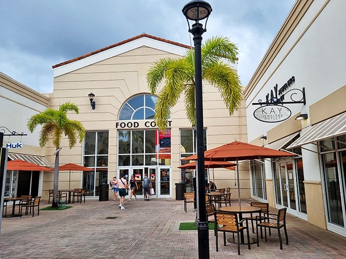 The Food Court: where shopping marathoners refuel before their second wind. The Switzerland of the outlet mall – neutral territory for tired feet.