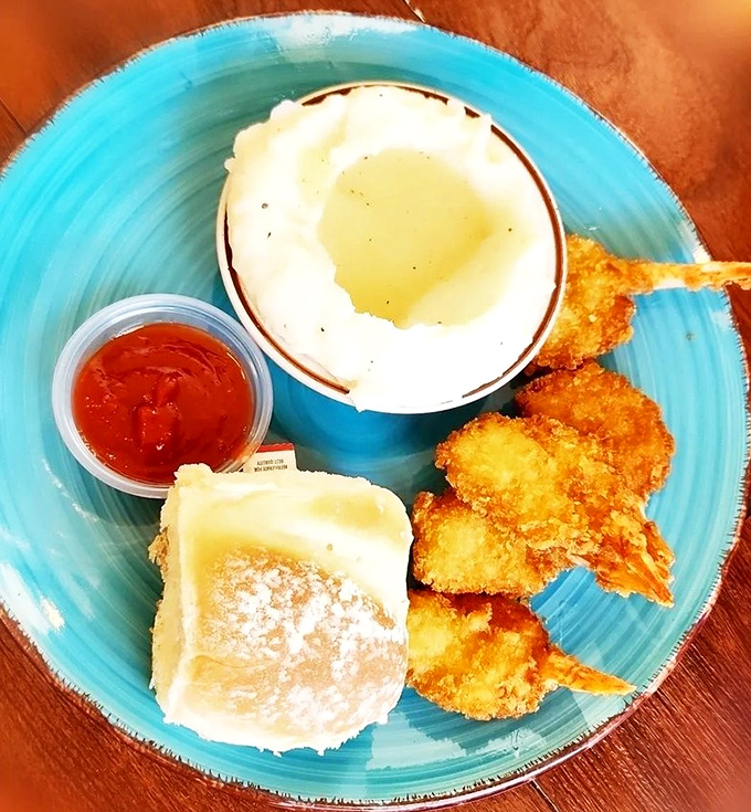 A blue plate special featuring golden fried shrimp, a fluffy roll, and what appears to be a side of mashed potatoes. Simple food done right never goes out of style.