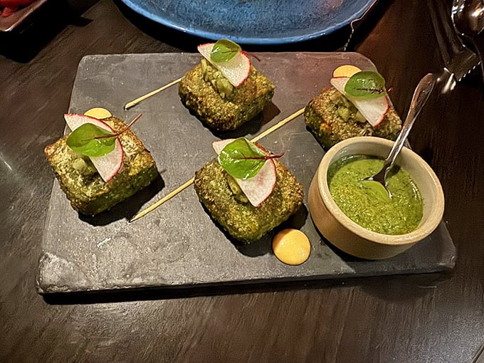 Hariyali Kebab squares present themselves like emerald jewels, adorned with radish medallions and mint chutney—proof that eating green can be an indulgence rather than a sacrifice.