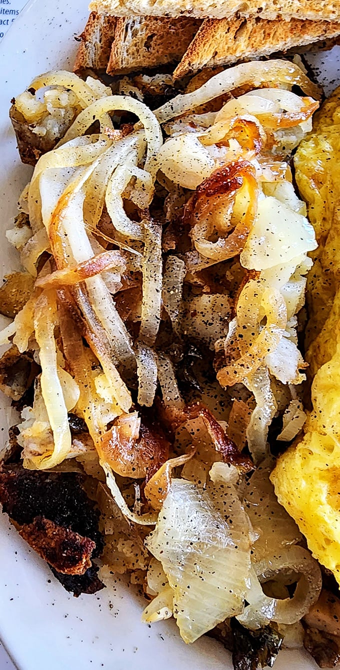 Caramelized onions dancing with home fries—proof that the simplest ingredients make the most memorable supporting acts.