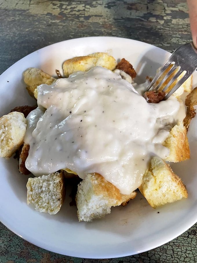 Comfort food architecture at its finest – tender chicken nestled under a blanket of gravy atop golden cubes of carb-laden bliss.