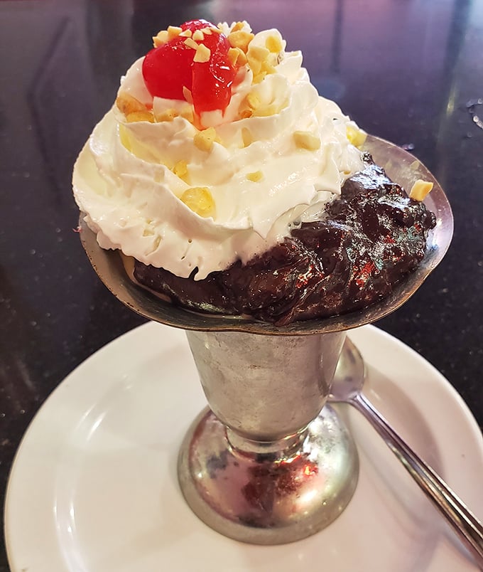 This hot fudge sundae isn't just dessert—it's architecture. The whipped cream tower defies physics while the cherry stands guard like a tiny red sentinel.