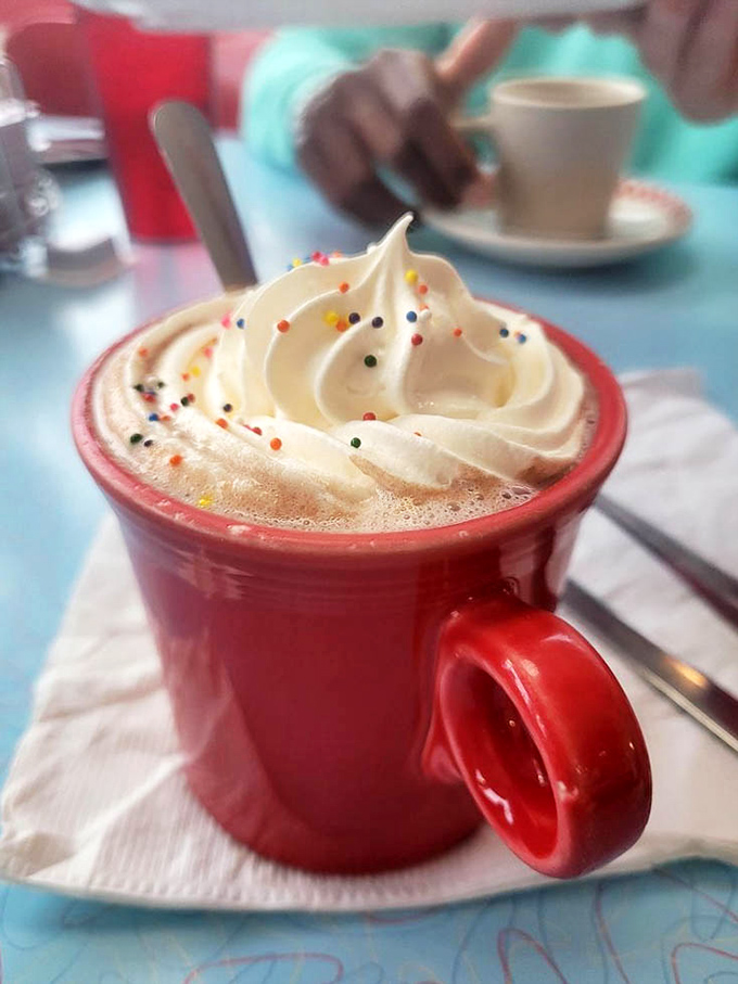 Hot chocolate crowned with whipped cream and sprinkles—proof that sometimes the best part of adulting is ordering dessert for breakfast.
