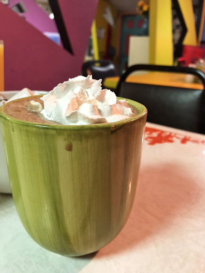 Hot chocolate served in a distinctive green mug with a cloud of whipped cream—the perfect companion for Erie's chilly mornings.