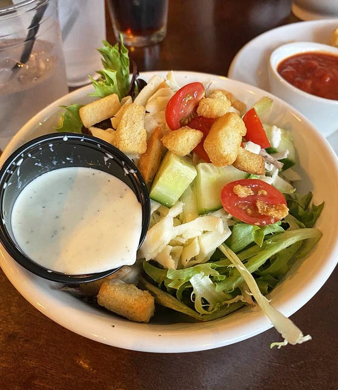 A house salad that actually deserves your attention. Crisp greens, fresh tomatoes, and those croutons—the supporting actors who secretly steal the show.