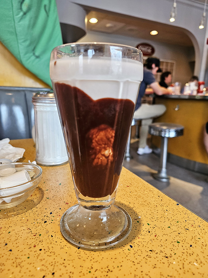 The chocolate egg cream—neither egg nor cream discusses—stands tall as a frothy testament to fountain drink perfection that transports you straight to Brooklyn.