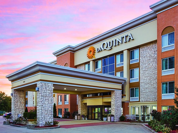 La Quinta's sunset-kissed facade offers weary travelers the golden promise of clean sheets and continental breakfast—the unsung heroes of any road trip.