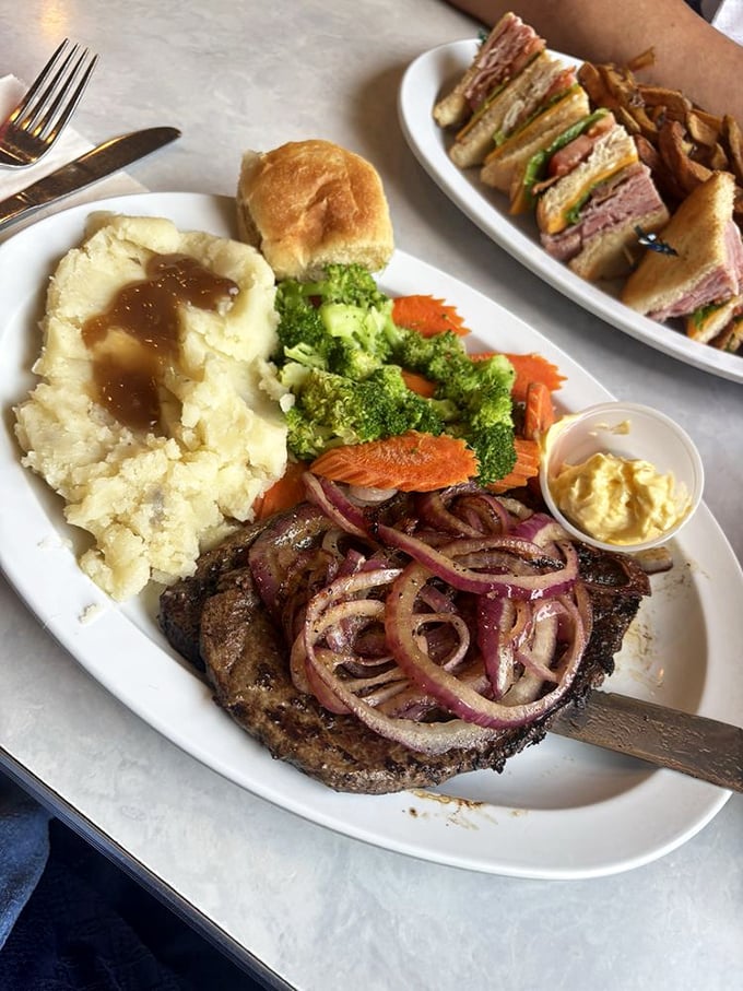 A plate that tells a story of comfort and tradition—tender steak topped with caramelized onions alongside mashed potatoes that could make a grown adult weep.
