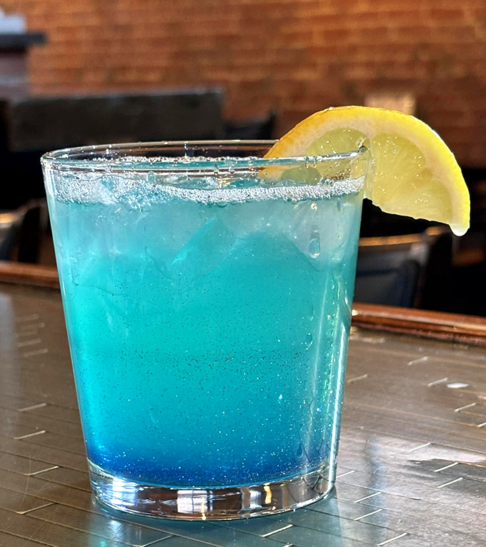 The Lunar Twilight cocktail glows an otherworldly blue, promising refreshment with a citrusy twist—like drinking a summer sky at sunset.