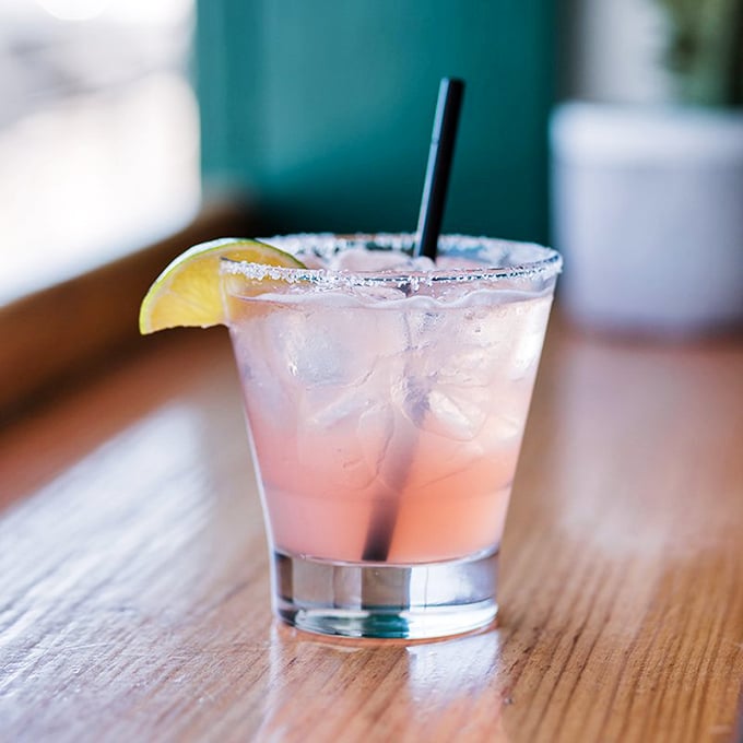 A sunset-hued cocktail that tastes like vacation—the salt rim and lime wedge promising momentary escape with each sip.