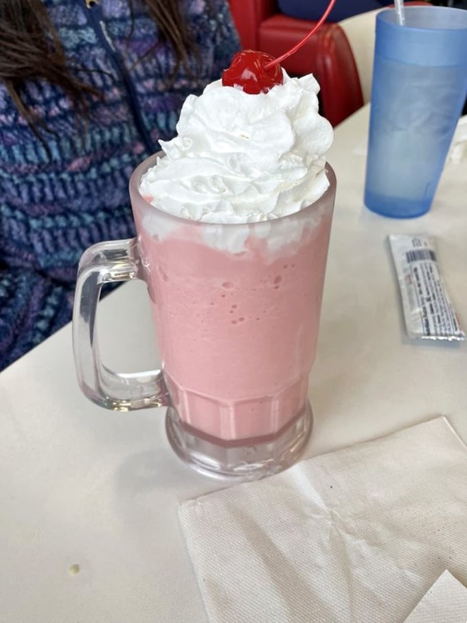 That strawberry milkshake isn't just pink—it's the exact color of childhood summer memories, topped with a cloud of whipped cream and nostalgia.