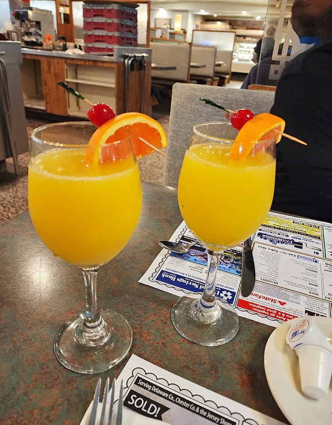 Mimosas at the diner—where breakfast meets celebration and orange juice finally fulfills its highest purpose, served with those little plastic swords of adulthood.