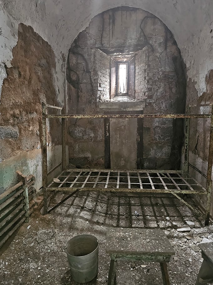 A stark reminder of confinement—rusted bed frame, crumbling walls, and a single bucket. Home sweet home for thousands over Eastern State's operational years.