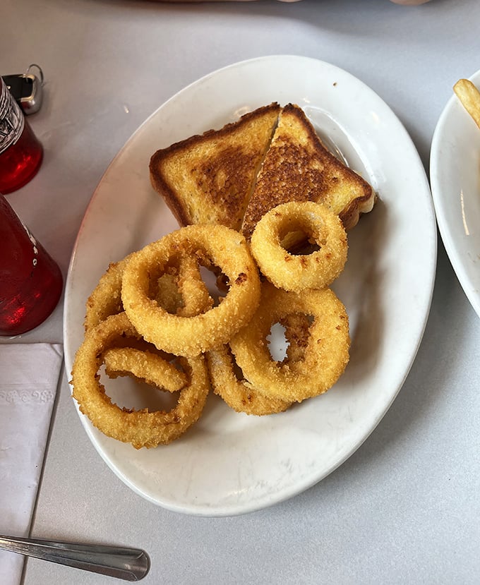 Onion rings the size of bracelets with a golden crunch that announces itself to everyone within earshot—comfort food jewelry at its finest.