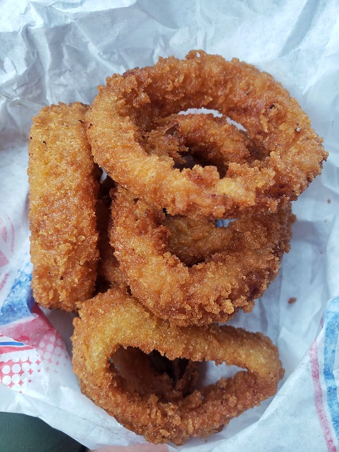 Golden-brown onion rings stacked like delicious jewelry – crispy, seasoned treasures that make you wonder why anyone would settle for ordinary fries.