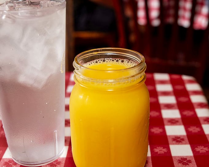 Mason jar of orange juice alongside ice water—because proper Southern hospitality means options for washing down those heavenly biscuits.