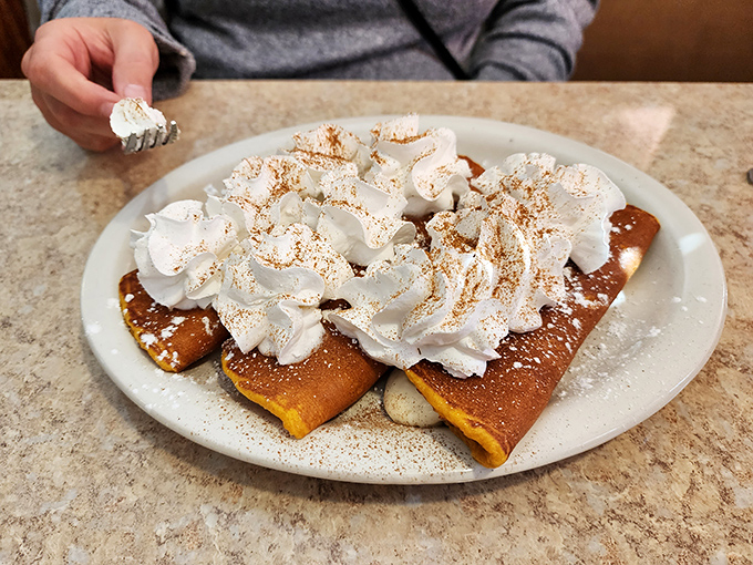 These pancakes aren't just topped with whipped cream—they're wearing a cloud that's been dusted with cinnamon for good measure.