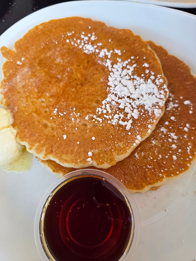 Golden pancakes dusted with powdered sugar, waiting for their maple bath. The kind of simple perfection that makes you question fancy brunch spots.