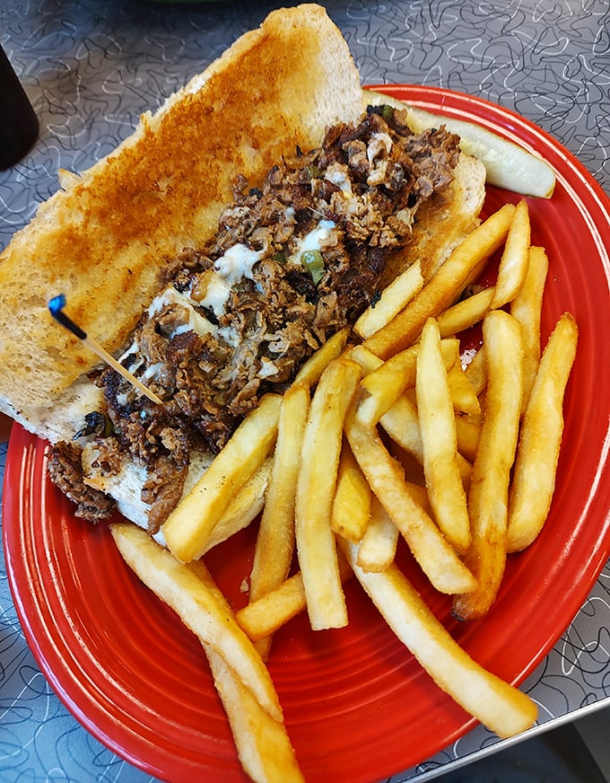 This isn't just a sandwich—it's a Philly masterpiece on a red plate runway, escorted by a golden honor guard of perfect fries.