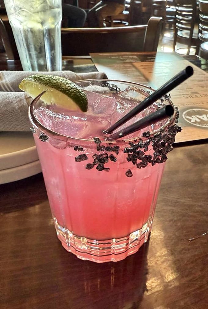 The pickled pear margarita isn't just a drink, it's a conversation piece—vibrant pink with a black salt rim that's as Instagram-worthy as it is delicious.