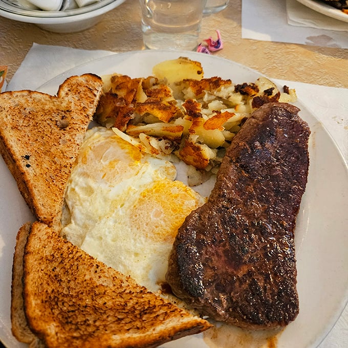 The classic American breakfast trinity—eggs, toast, and steak—executed with the kind of precision that makes you question every other breakfast you've had.