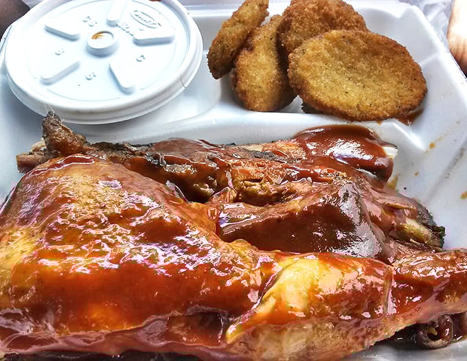 Fried cornmeal hush puppies alongside sauce-slathered chicken—proof that sometimes the best things in life come in styrofoam containers.