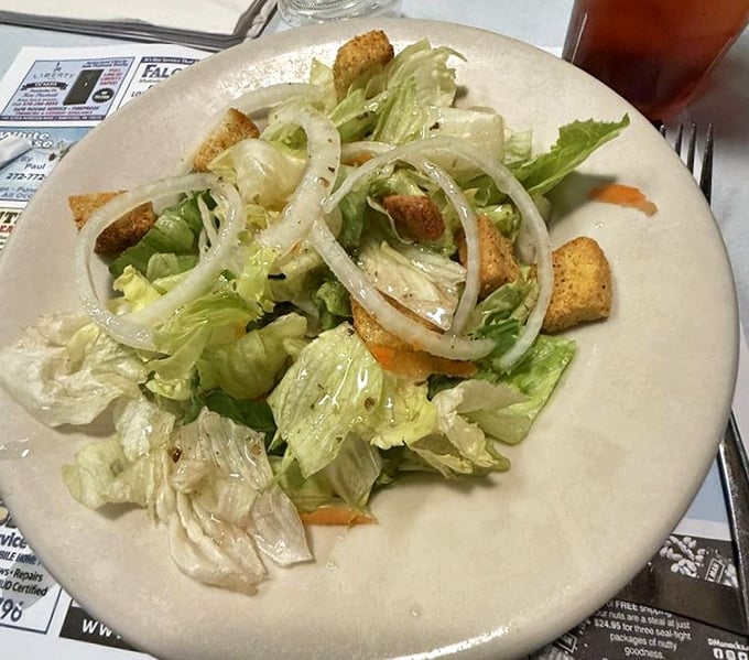 A simple house salad that knows its role—the opening act before the headliner arrives, with crisp lettuce and those perfectly thin-sliced onions.