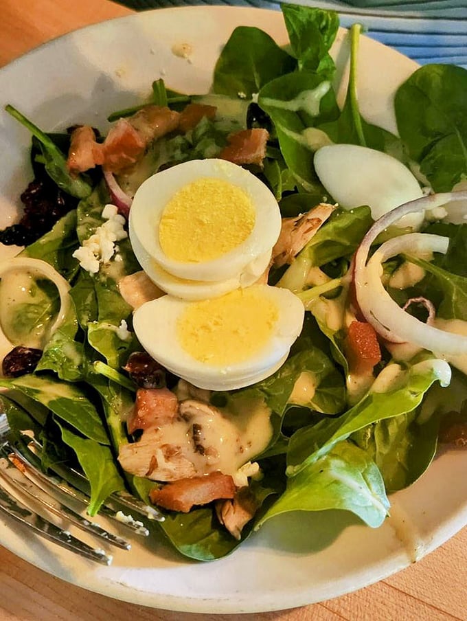 A spinach salad that makes eating greens feel like an indulgence rather than a obligation—proof that vegetables can party too.