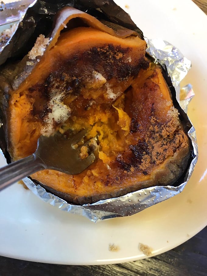 That sweet potato looks like it's been tucked into a foil sleeping bag and roasted until caramelization works its magic—comfort food that Mother Nature herself designed.