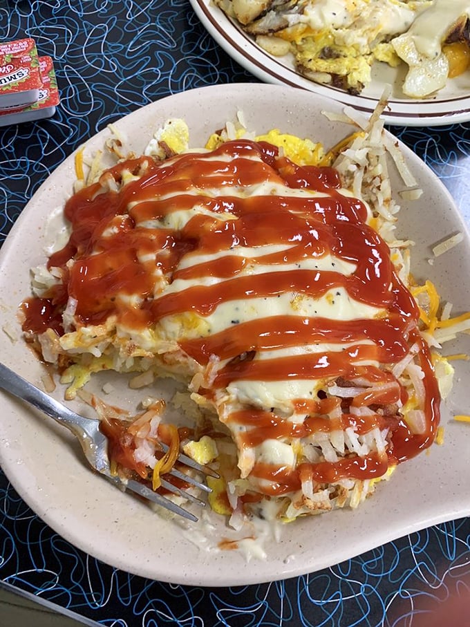 Breakfast architecture at its finest – eggs, hash browns, and cheese layered with precision, then baptized with just the right amount of ketchup.