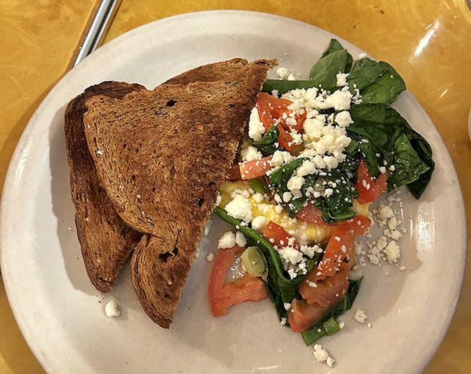 Fresh ingredients transform scrambled eggs into a colorful breakfast canvas. The feta cheese adds tangy punctuation to this morning masterpiece.