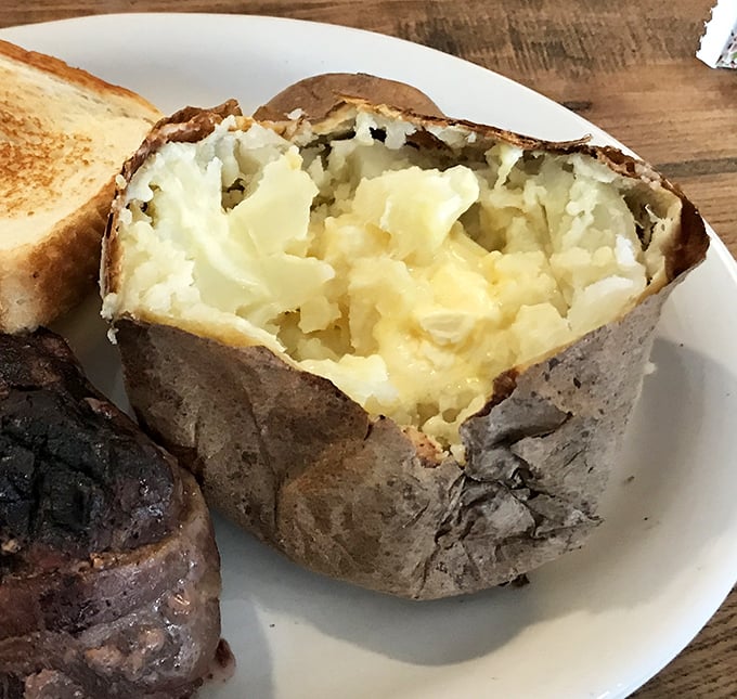 Behold the humble baked potato in all its glory – a fluffy interior waiting patiently for your butter and sour cream artistic expression.