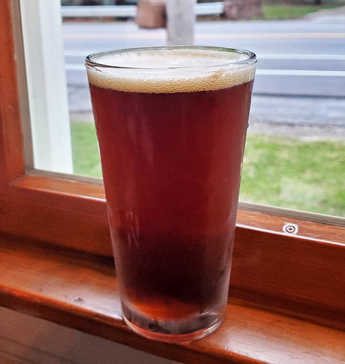 A perfectly poured amber brew catching window light – because sometimes the best companion to lake-fresh fish is a cold one with a view.