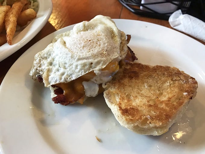 Breakfast sandwich architecture at its finest—where the sunny-side egg becomes both structural element and sauce in one brilliant move.