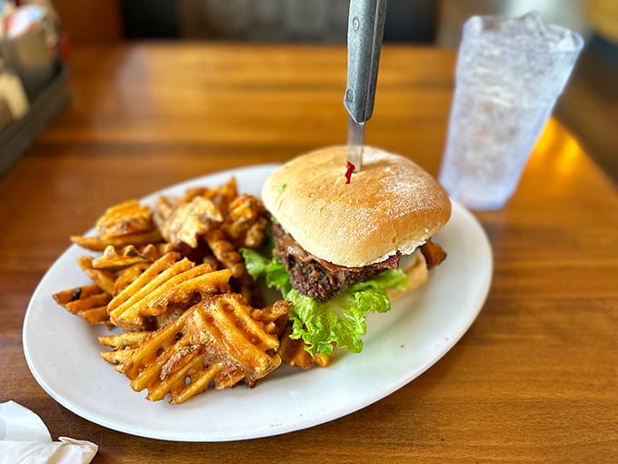 Not just a burger, but a hand-crafted monument to beef, complete with a knife standing proudly at attention like it's guarding deliciousness.