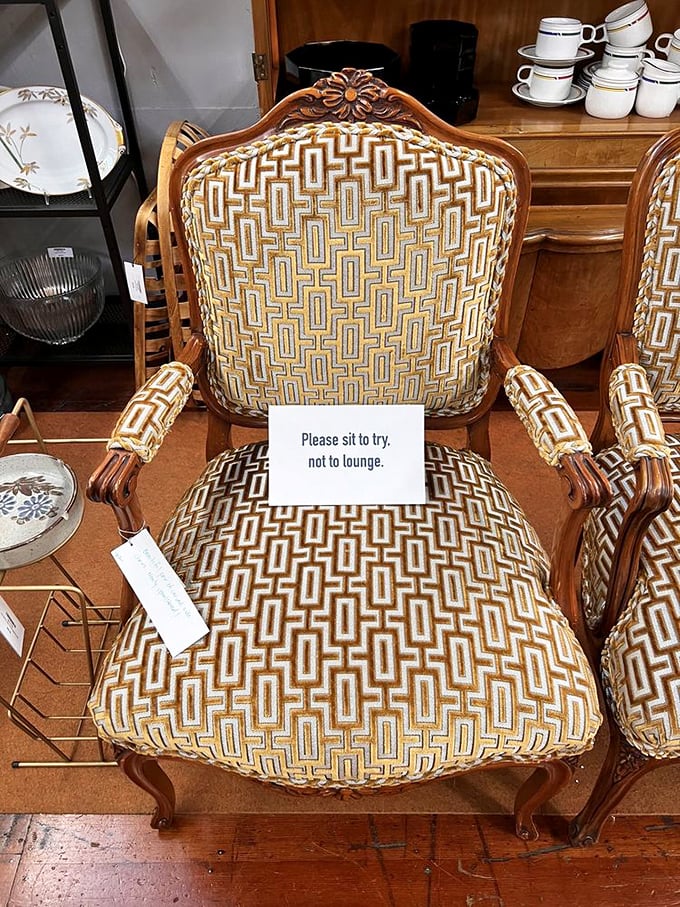 "Please sit to try, not to lounge." The chair's geometric upholstery screams 1970s sophistication, while the sign whispers, "But don't get too comfortable."