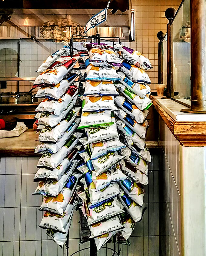 The mountain of chip bags isn't decoration—it's a testament to the volume of hungry customers who make the pilgrimage to this sandwich sanctuary.