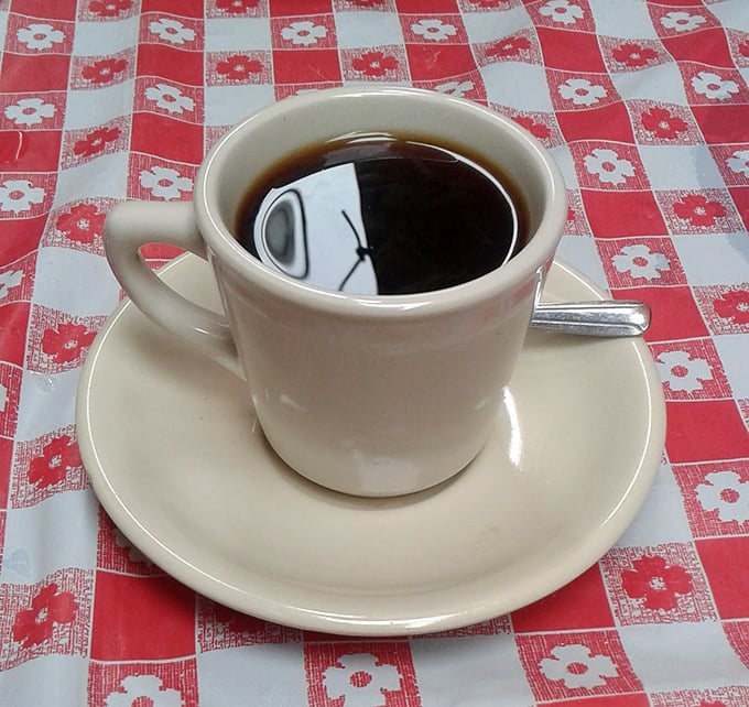 Simple pleasures in a classic mug. Nothing fancy here—just honest-to-goodness coffee served on a checkered tablecloth, exactly as the coffee gods intended.