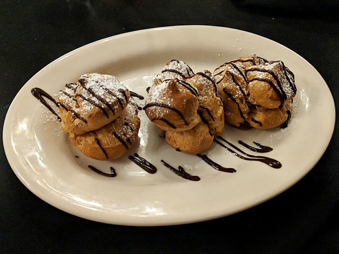 Cream puffs that defy gravity – light as air yet somehow substantial, drizzled with chocolate in a dessert that whispers rather than screams indulgence.